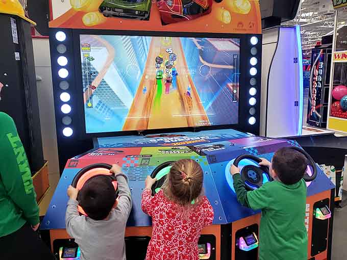 Young gamers huddle around racing simulators, their concentration rivaling surgeons performing delicate operations on digital highways.