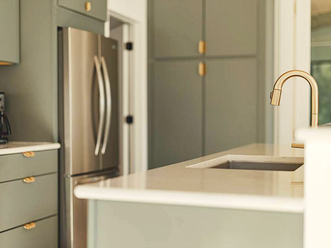 Even the kitchen sink gets the designer treatment with that elegant brass faucet arching over pristine white countertops.