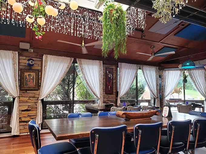 Dining spaces draped with curtains and decorated with hanging plants, creating cozy corners throughout this eclectic wonderland.