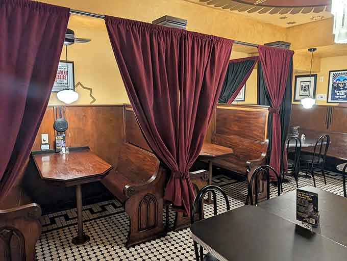 Private booths with velvet curtains add a touch of old-school romance perfect for date nights or secret conversations.