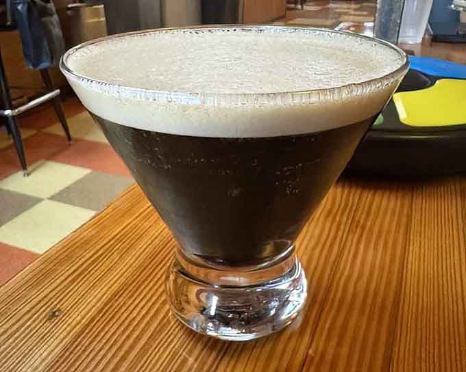 An espresso martini sits pretty on checkered flooring, looking sophisticated enough to impress even the pickiest cocktail enthusiast.