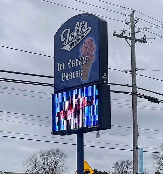 The vintage-style roadside sign glows with pride, advertising ice cream parlor excellence visible from blocks away at night.