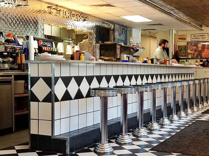 Chrome-topped counter stools lined up like soldiers, each one offering a front-row seat to the delicious action happening behind the counter.