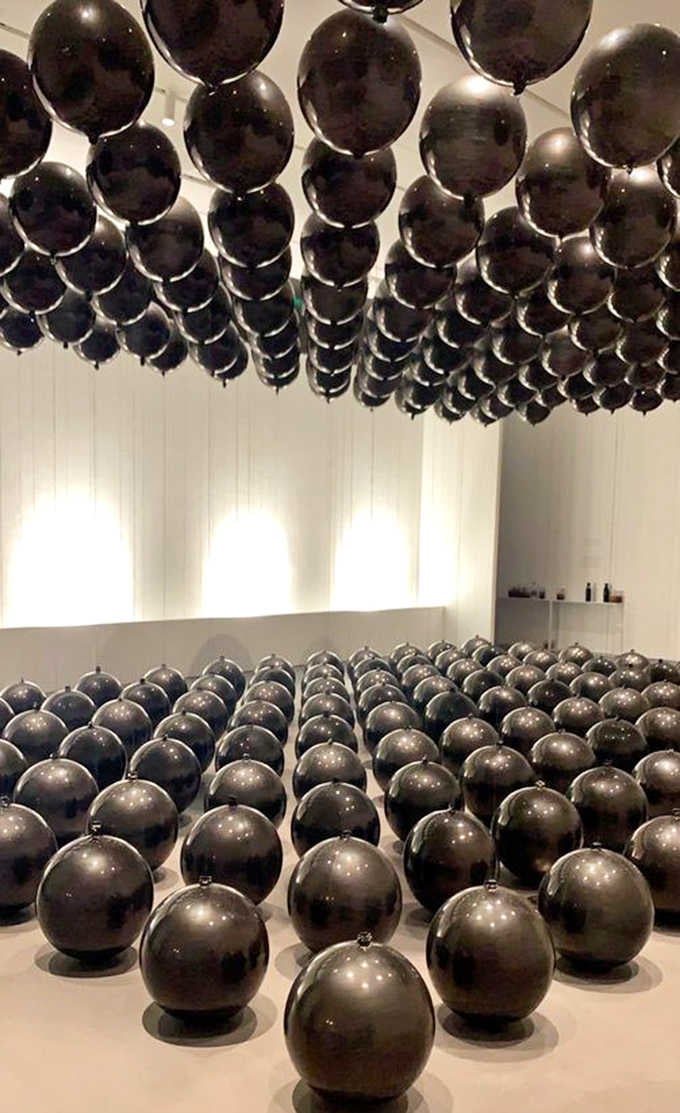 Black spheres multiply like something from a surrealist's fever dream, creating patterns that hypnotize your eyeballs.