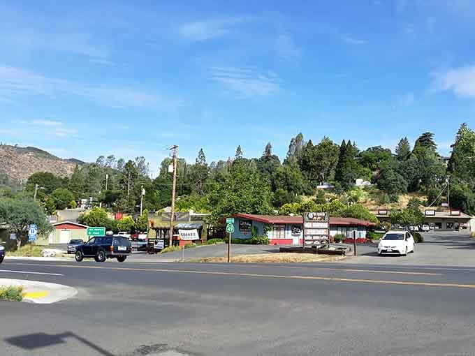 Tree-covered hills provide the backdrop for this roadside scene where small-town California life continues at its own unhurried, pleasant pace.