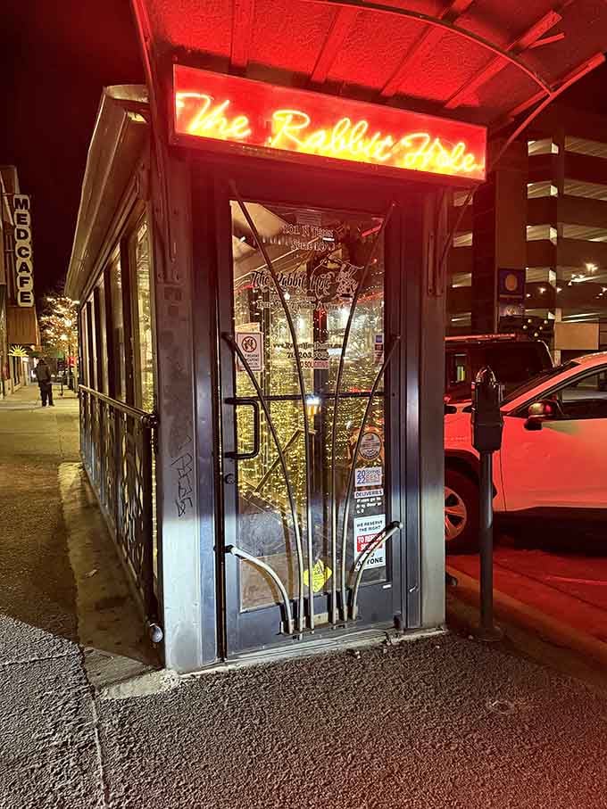 Evening transforms this whimsical doorway into a glowing portal promising craft cocktails and adventures in a subterranean wonderland below.