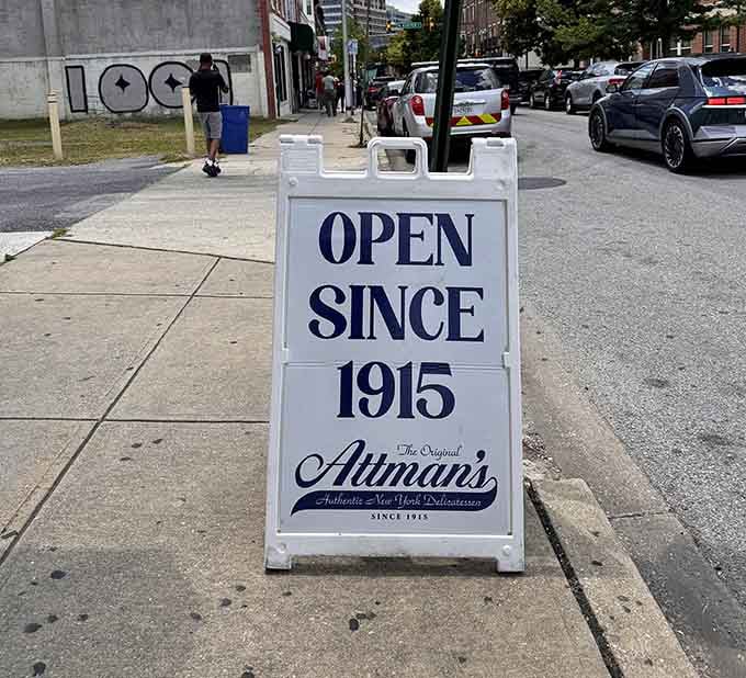 A sidewalk sign proudly announcing over a century of service, because some traditions deserve to be celebrated daily.