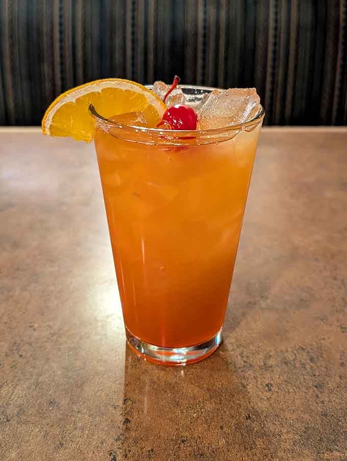 A perfectly crafted cocktail garnished with orange and cherry, ready to complement your upcoming feast beautifully.