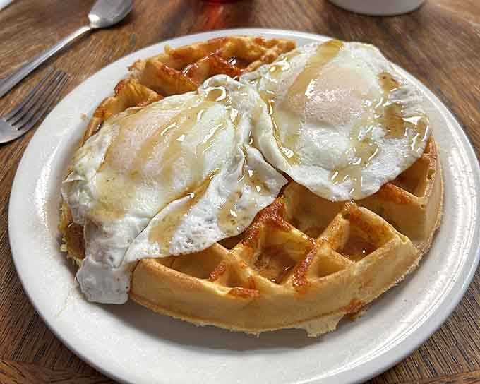 Sunny-side eggs crown a waffle that's been drizzled with syrup and sprinkled with pure breakfast magic.