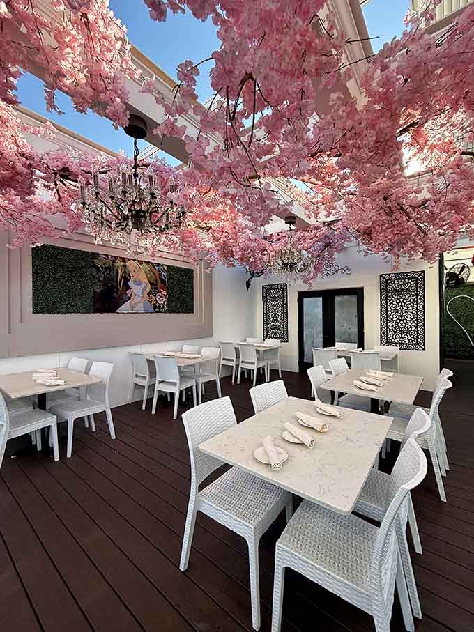 Pink cherry blossoms bloom eternally on this rooftop patio where Mediterranean dining meets perpetual spring under open skies.