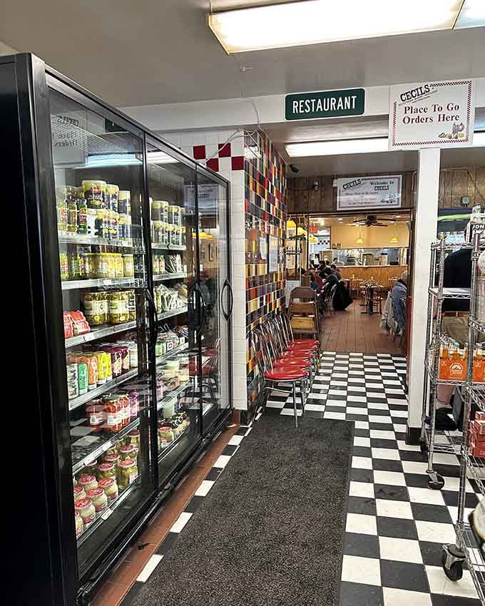 The classic black and white checkered floor leads you past coolers and shelves toward sandwich paradise, building anticipation with every step forward.