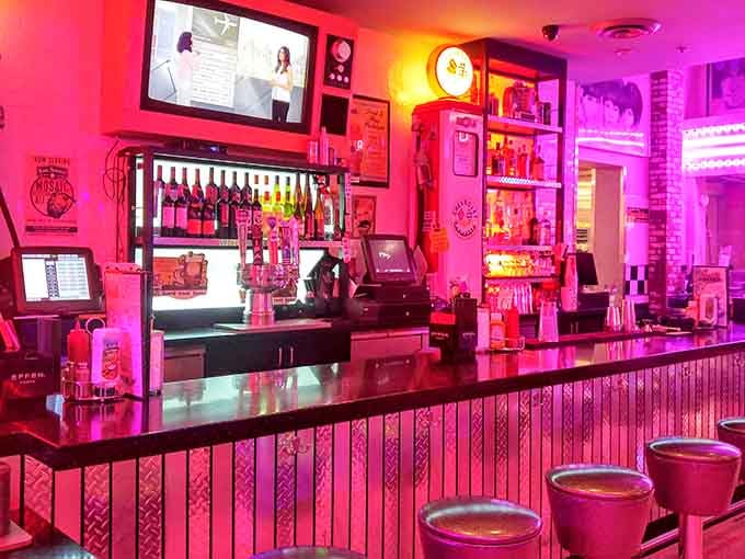 The bar glows pink like a sunset made of nostalgia, serving drinks to adults who remember when diners ruled.