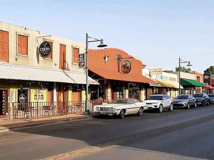 Classic cars cruise past colorful storefronts in a scene that could've been plucked straight from a 1950s movie set.
