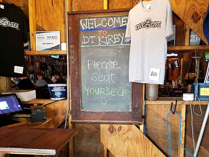 "Please seat yourself" written on chalkboard with t-shirts hanging nearby captures that laid-back, friendly welcome perfectly.
