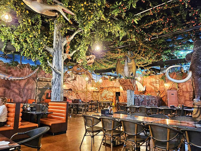 Fossil skeletons peek through rocky formations while diners enjoy their meals beneath a canopy of ancient foliage and twinkling lights.