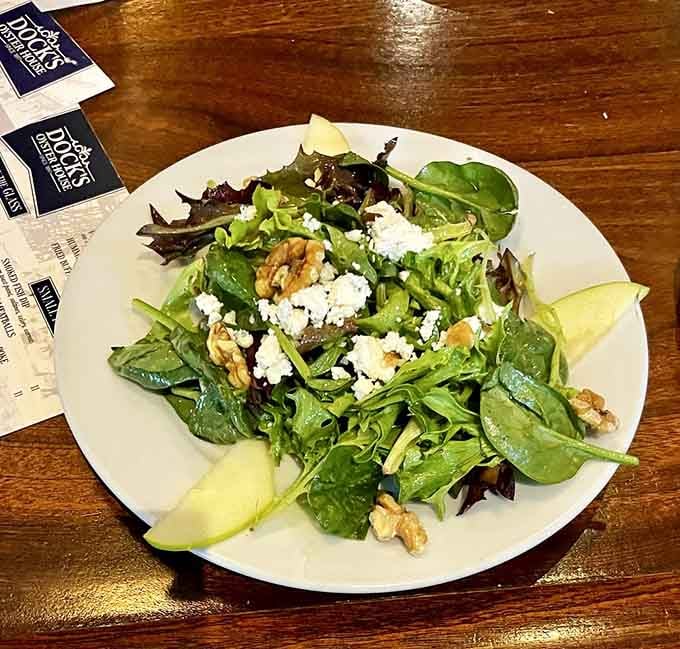 A salad featuring fresh greens, pears, and walnuts for those pretending they came here for anything besides seafood.