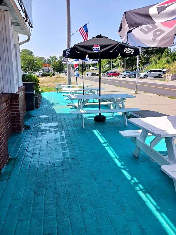 White picnic tables on turquoise pavement create the perfect summer dining spot for enjoying Rochester's burger royalty outdoors.