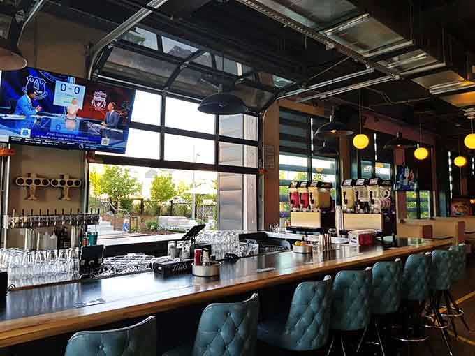 Teal leather bar stools face taps and screens; this is where thirst gets quenched and games get watched properly.