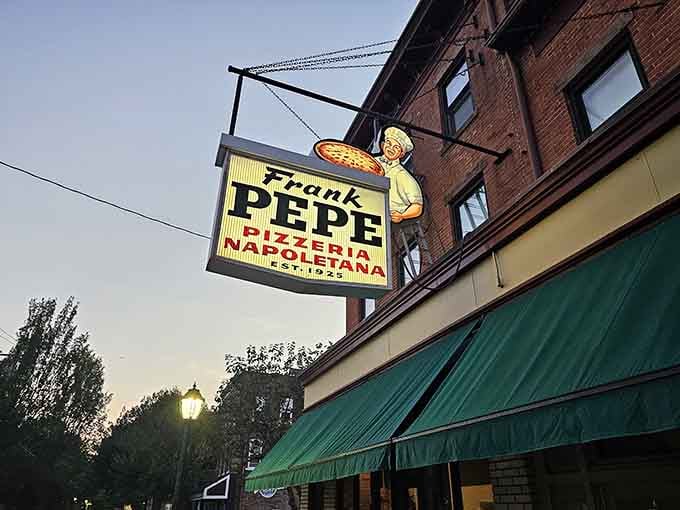 The vintage sign glowing at dusk, a beacon calling pizza lovers home like a carb-loaded lighthouse of hope.