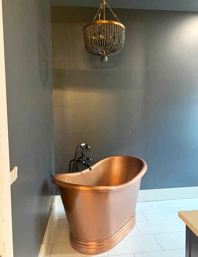 That gleaming copper soaking tub under a beaded chandelier makes every bubble bath feel like a coronation ceremony.