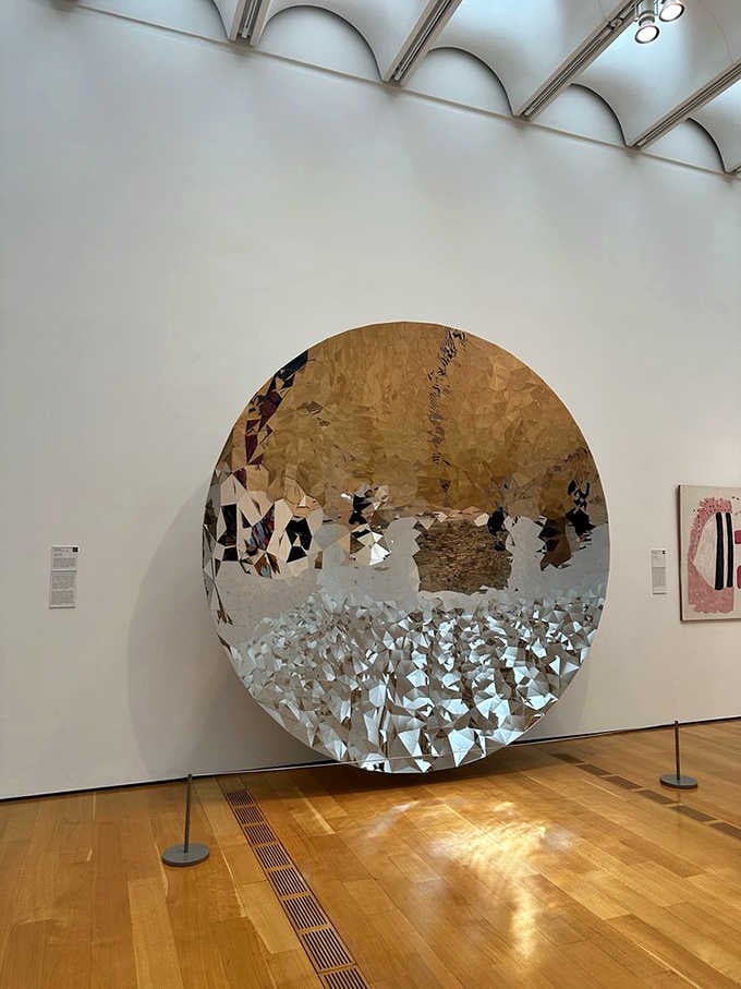 A massive circular mirror reflecting fragments of reality, making you question what's real and what's reflection.