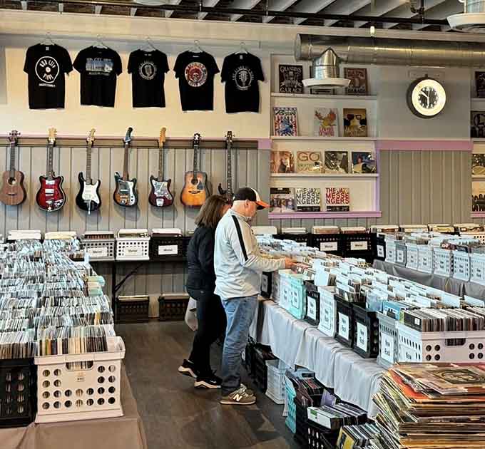 Fellow diggers browse the bins with focused intensity – this is serious business disguised as casual weekend fun.