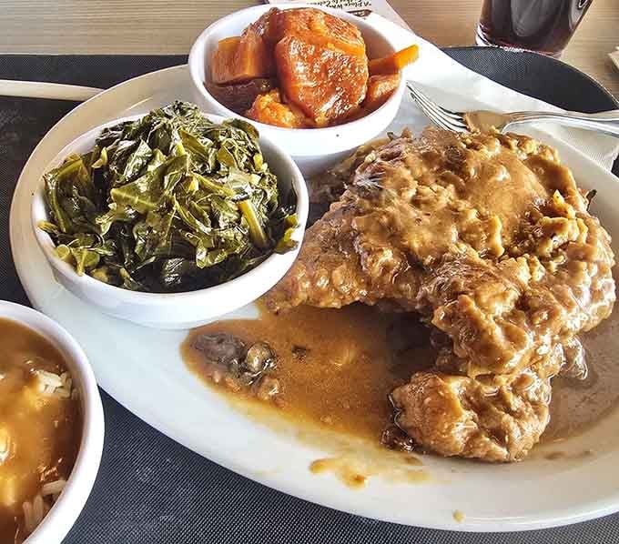 Smothered pork chop swimming in gravy with candied yams is basically edible joy on a plate.