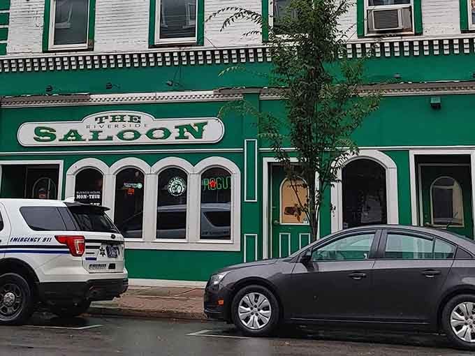 The Riverside Saloon's green facade announces itself boldly, promising cold drinks and conversation without the pretentious craft cocktail markup.