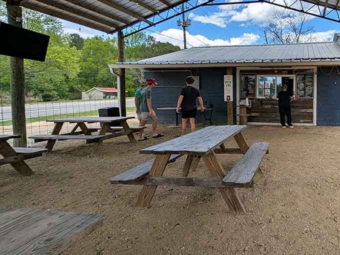 Wooden picnic tables scattered across the sandy lot create the perfect casual atmosphere where strangers become friends over shared appreciation for exceptional smoked meat.