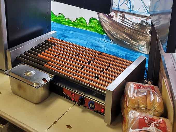 The roller grill keeps those franks spinning toward perfection, a mesmerizing dance of heat and deliciousness in constant motion.