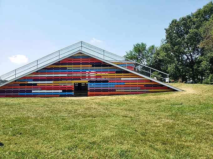 Colorful horizontal stripes create an architectural rainbow that somehow makes perfect sense nestled into this grassy hillside setting here.