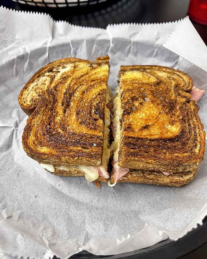 Grilled rye bread embracing corned beef and melted Swiss in a Reuben that honors the sandwich hall of fame.