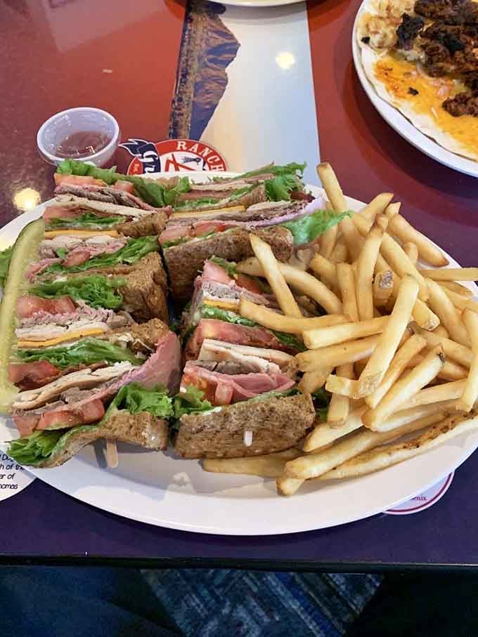 Club sandwich stacked high with turkey, bacon, and vegetables gets quartered for easier handling, though you'll still need strategic planning here.