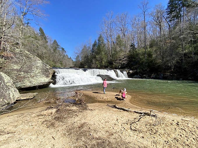 Visitors wade in the shallow waters, living proof that this swimming hole delivers on its promise of refreshing mountain coolness.
