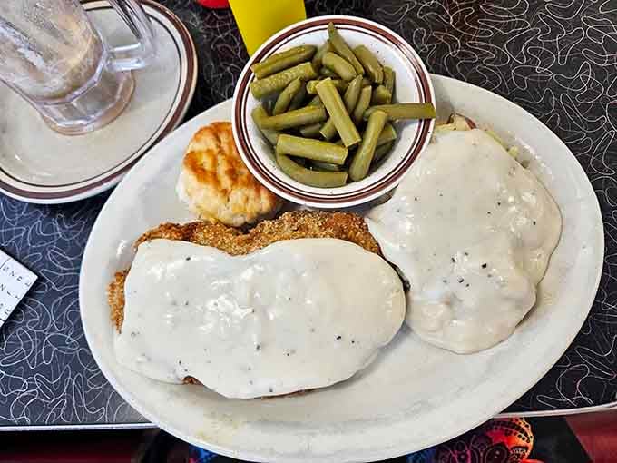 Chicken fried steak smothered in gravy, served with green beans and a biscuit for good measure.