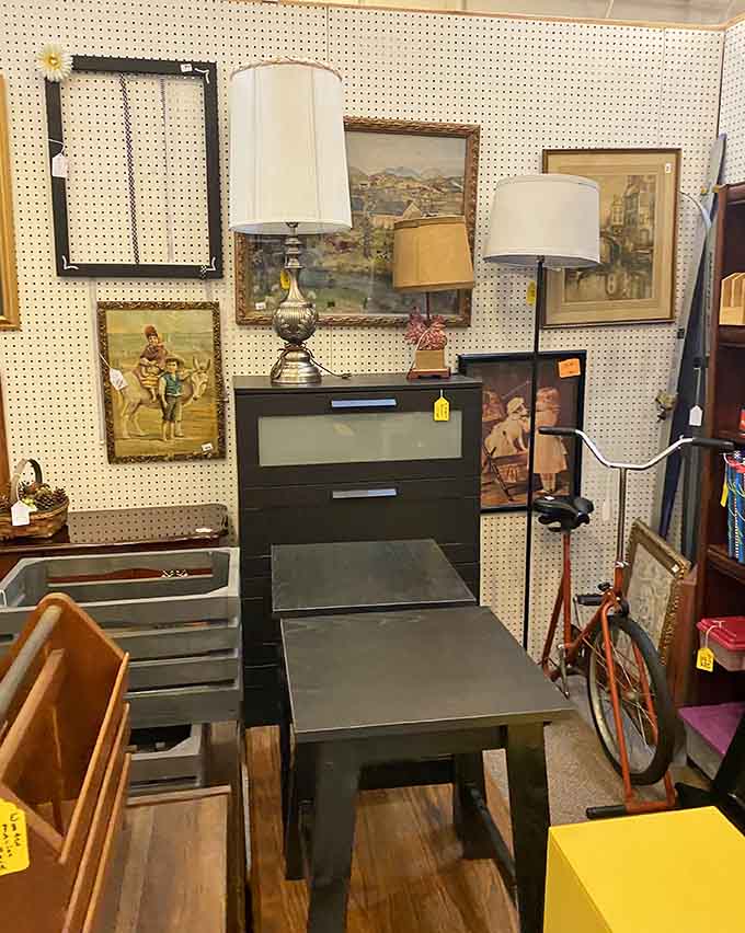 Lamps and artwork proving that pegboard walls are the unsung heroes of antique mall organization everywhere.