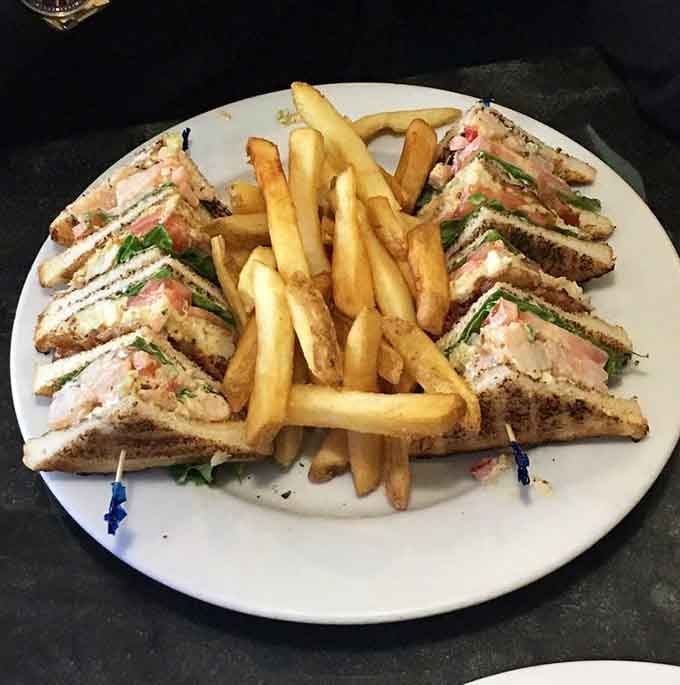 This club sandwich towers with layers of flavor, proving that sometimes more is more, especially when fries are involved.