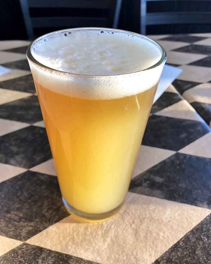 A cold beer with a perfect foam head, ready to wash down approximately seventeen slices of pizza.