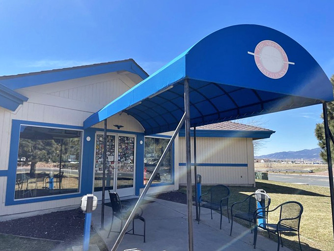 The entrance welcomes you with blue awnings and outdoor seating, perfect for pre-flight dining under Colorado's endless sky.