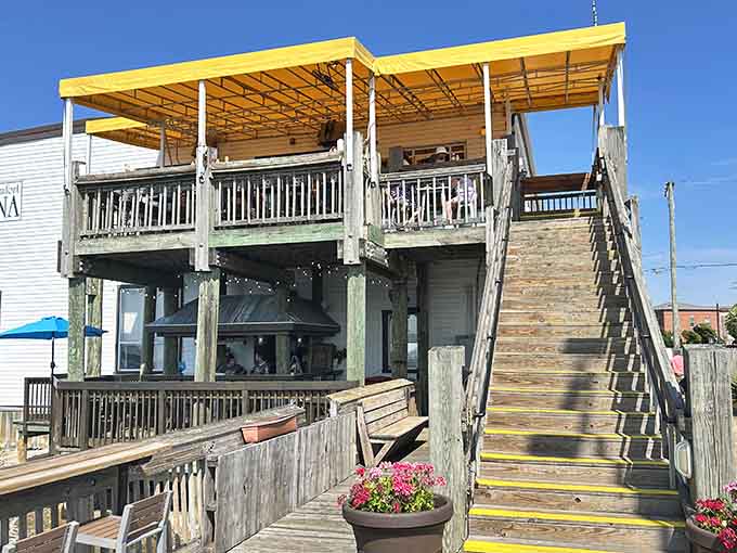 The outdoor deck with yellow canopy offers elevated waterfront dining where boats and breezes become part of your meal experience.