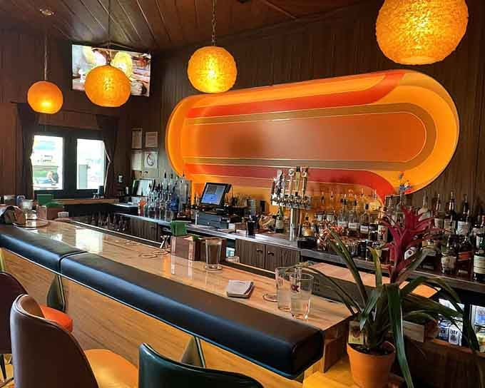 The bar area glows with orange accents and globe lighting, creating an atmosphere that's simultaneously energetic and relaxed.