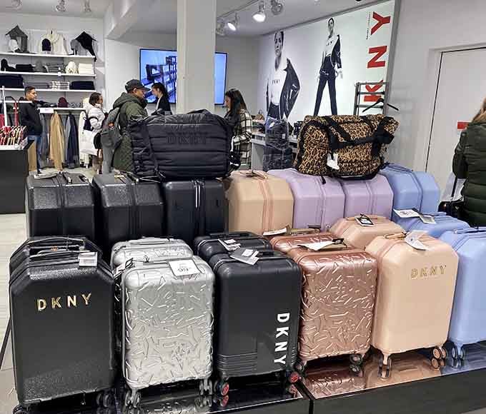 DKNY luggage stacked like colorful building blocks, ready to accompany you on adventures funded by all the money you just saved.