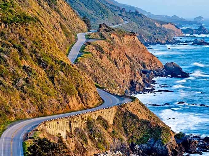 Serpentine curves hug cliffsides where every turn reveals another reason to pull over and gawk shamelessly.