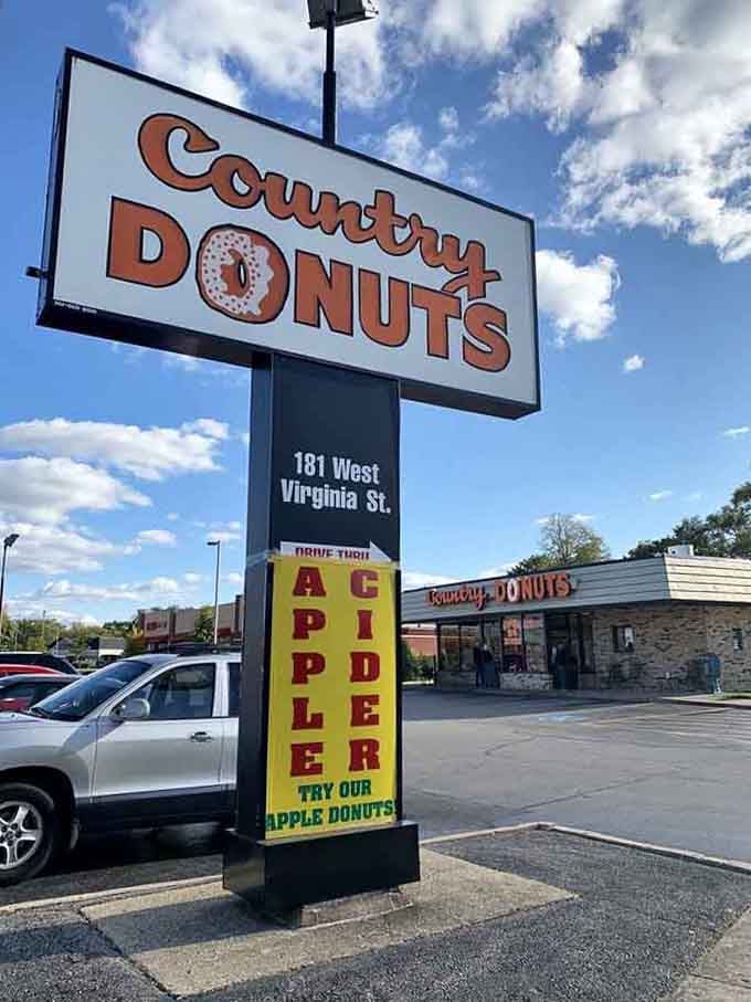 The roadside sign advertises apple cider donuts, proving that even billboards can make your mouth water from distance.