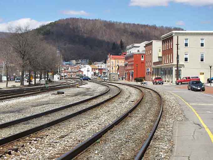 Railroad tracks curving through town with mountains beyond, because Cumberland never forgot it was built on going places, literally and figuratively.
