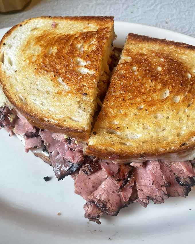 Tender sliced meat piled between griddled rye bread makes this Reuben a testament to the enduring power of classic deli-style sandwiches.