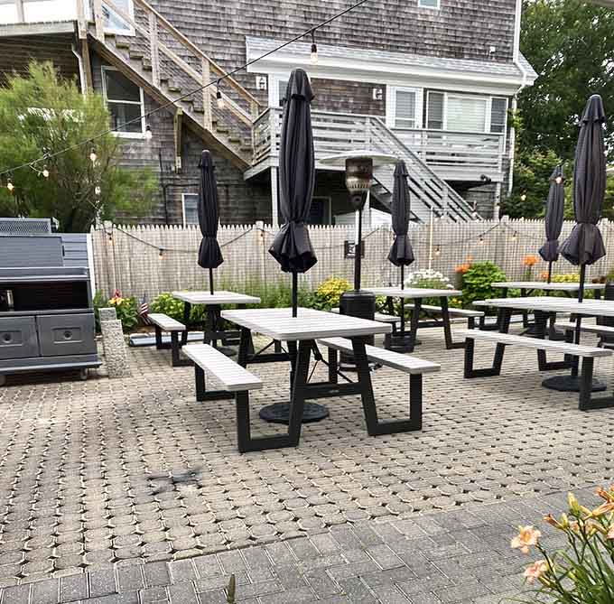 Outdoor patio seating with umbrellas ready for sunny days, where dining al fresco means communing with Provincetown Harbor itself.