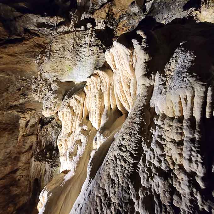 Delicate white flowstone formations cascade downward like elaborate drapery designed by nature's most patient interior decorator ever.