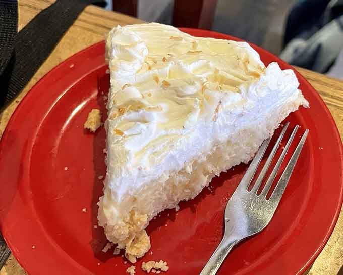 Coconut cream pie with towering meringue that defies gravity and common sense, making dessert stomach suddenly appear from nowhere.