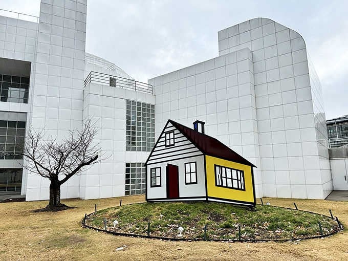 Roy Lichtenstein's house sculpture sits cheerfully outside, like a comic strip escaped into three dimensions.